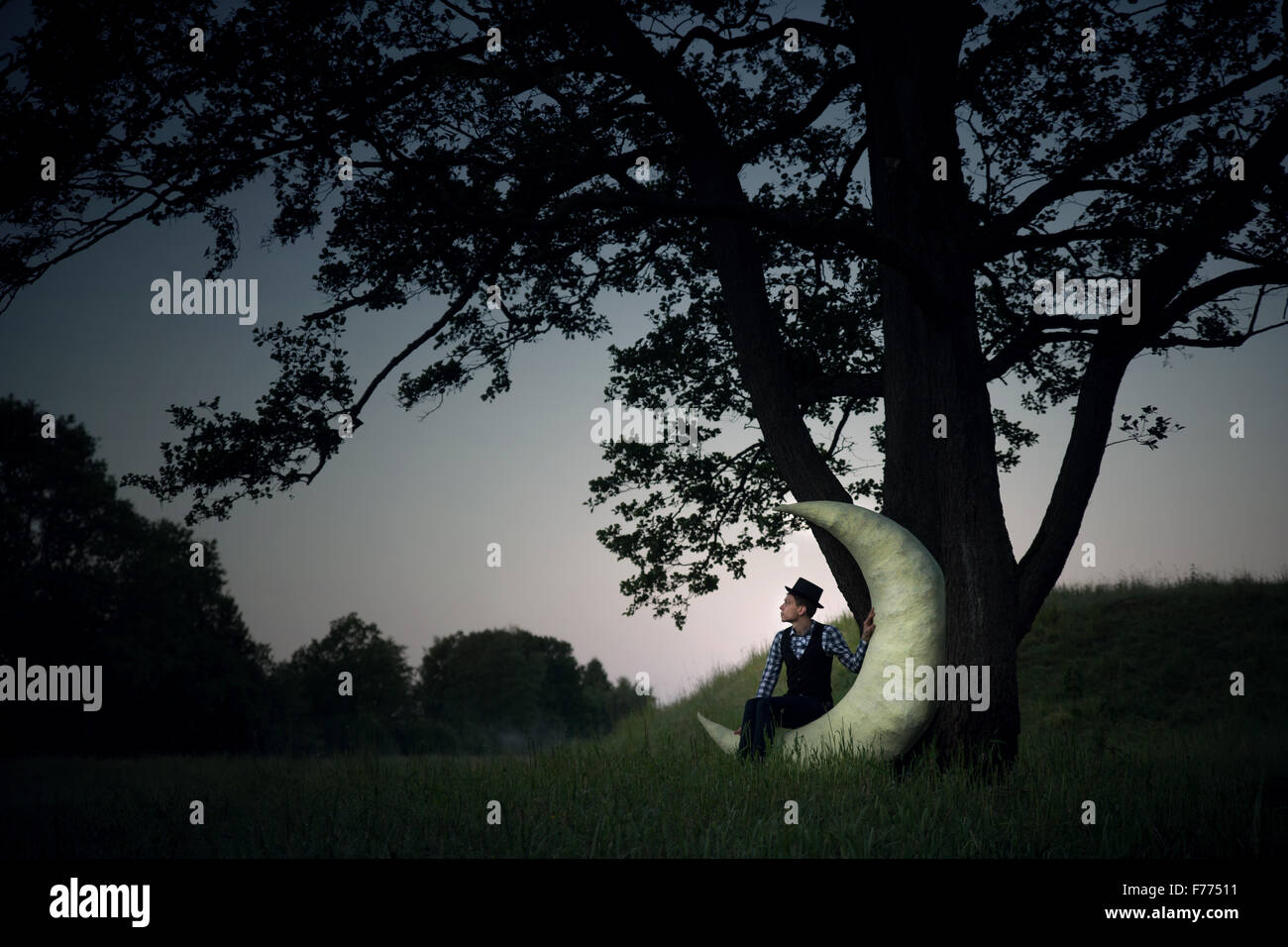 Man sitting in the moon, crescent moon, under tree, at dusk Stock Photo ...