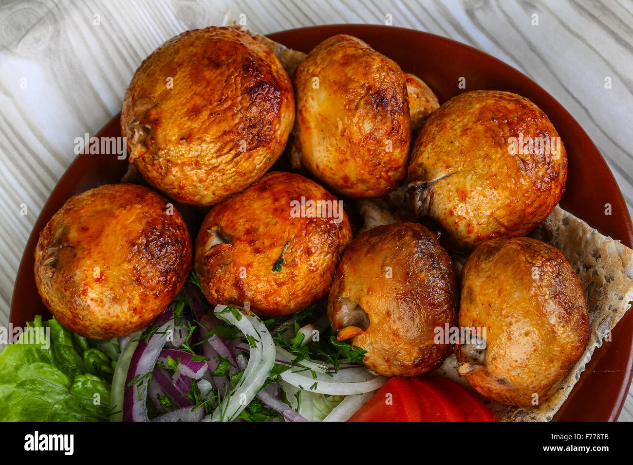 Grilled champignons with herbs, spices - served onion rings, tomato and ...