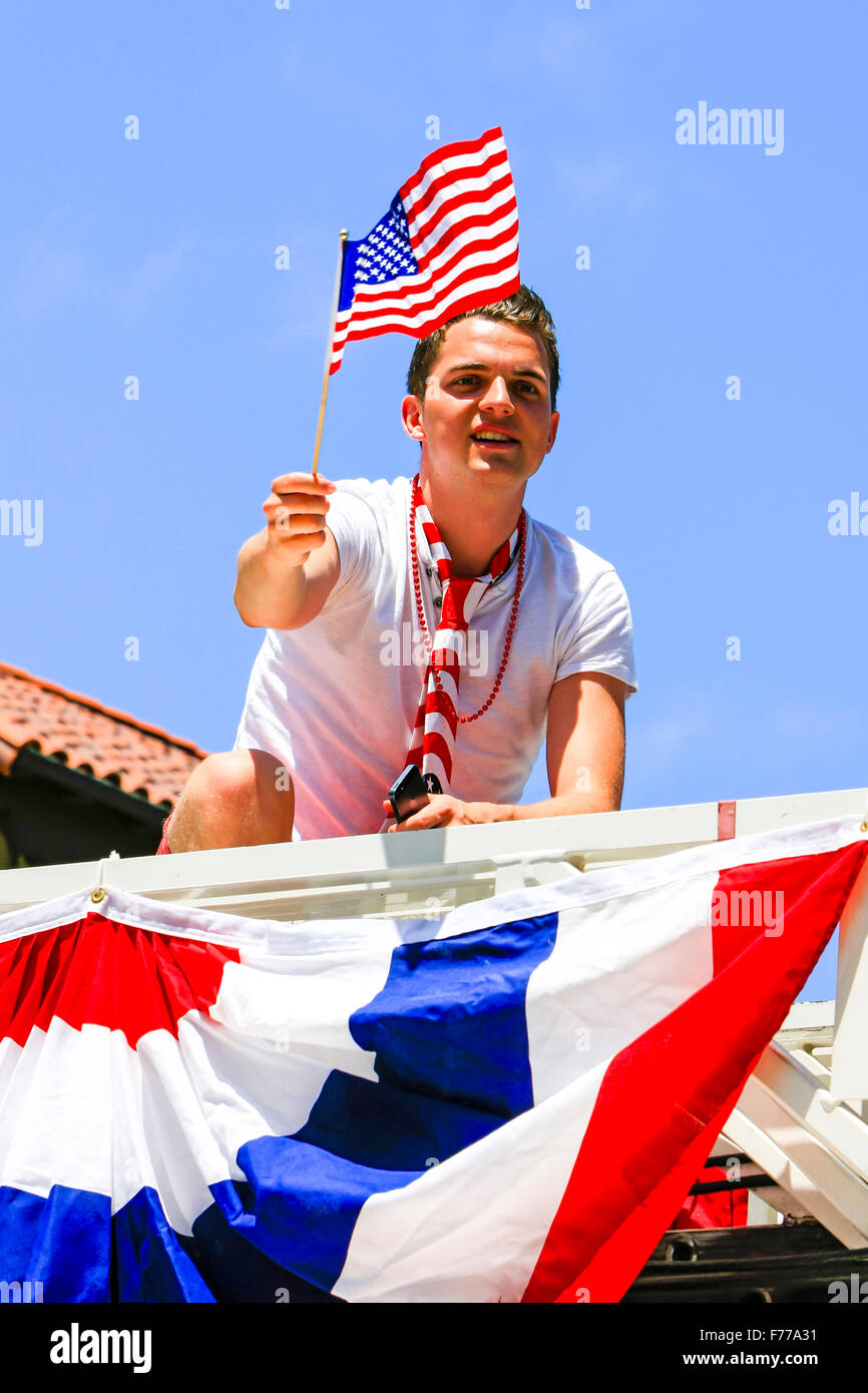 Patriotic young man waves a US flag on July 4th celebrating his ...