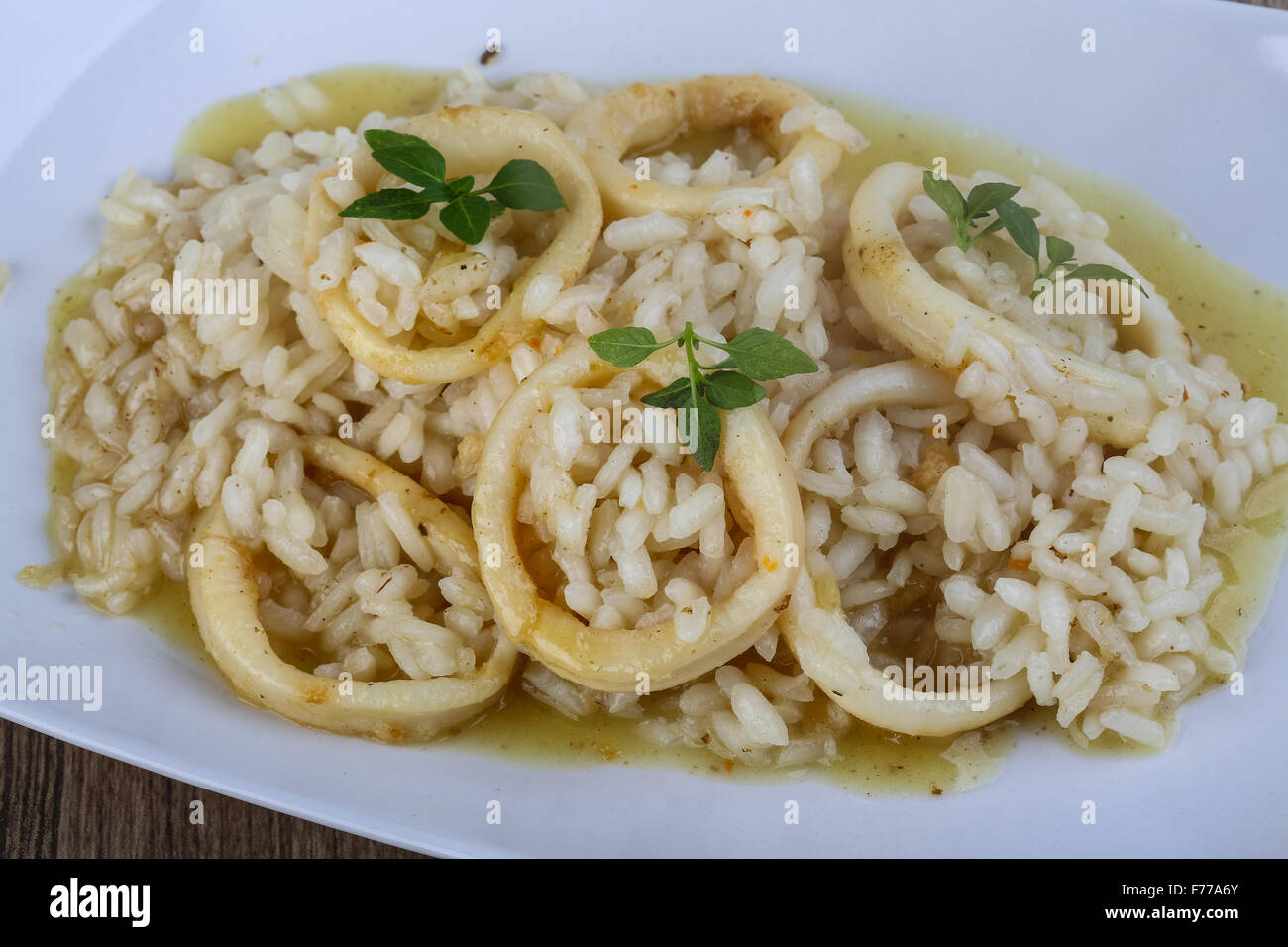 Italian famous cuisine - Squid risotto served basil leaves Stock Photo ...