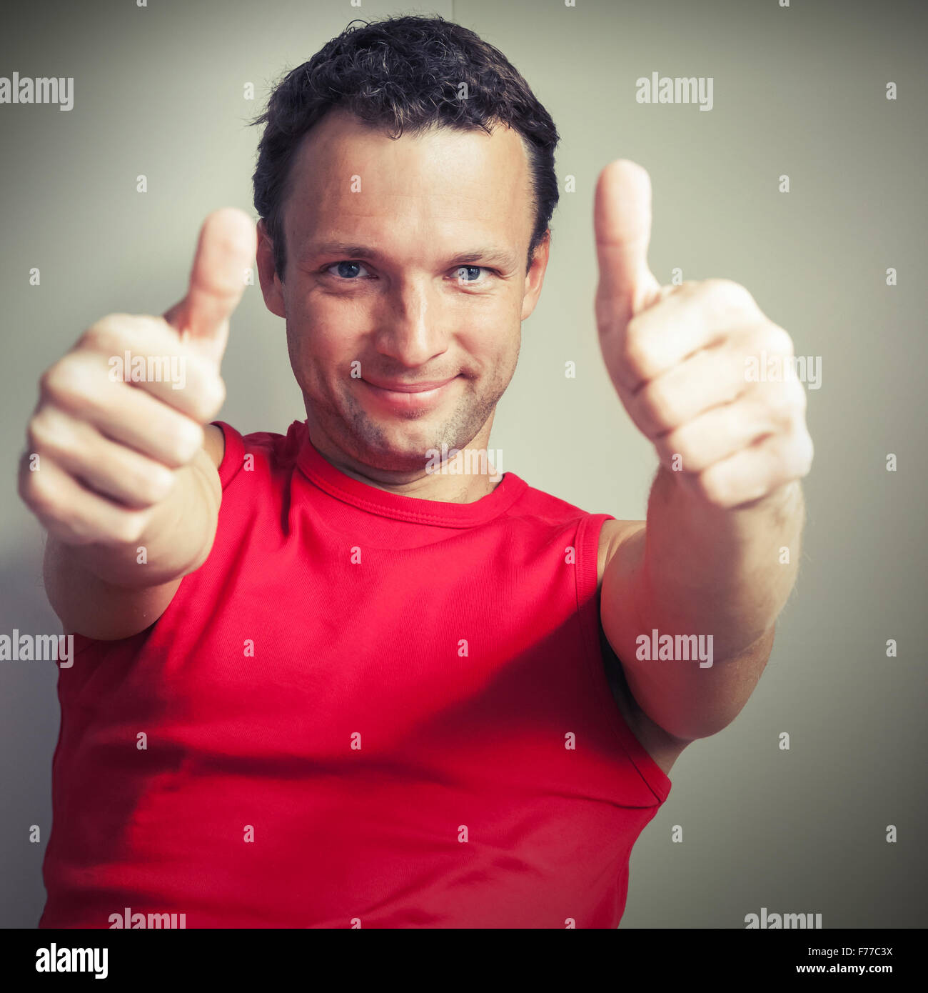 Positive young smiling man shows thumbs up, square photo with vintage ...