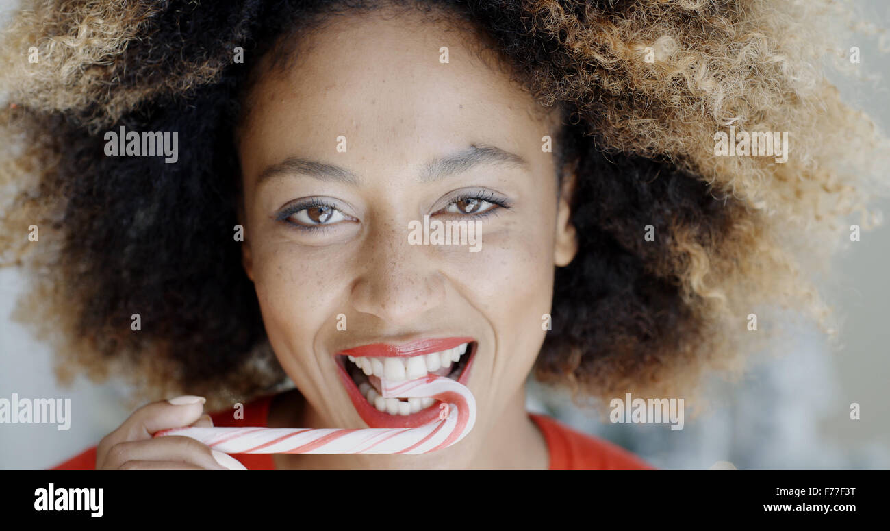 Young woman biting a festive candy cane Stock Photo - Alamy
