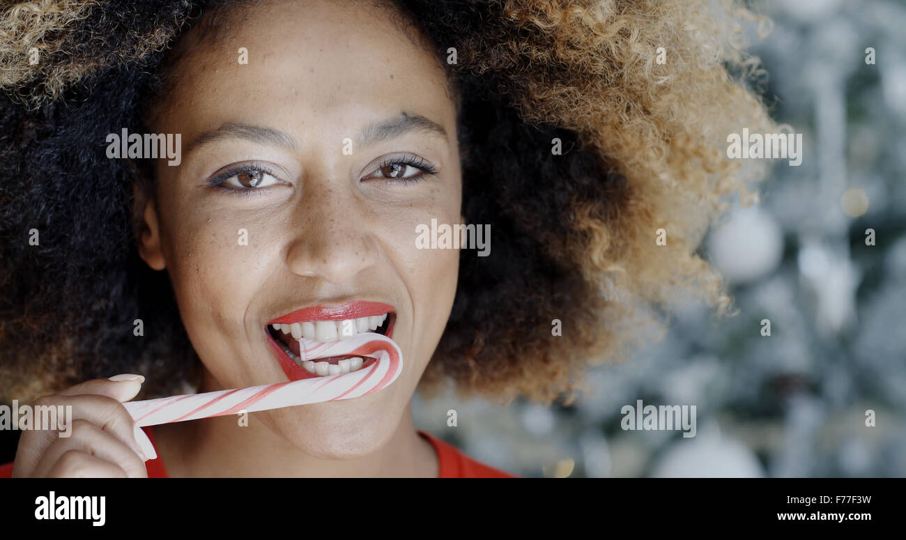 Young woman biting a festive candy cane Stock Photo - Alamy