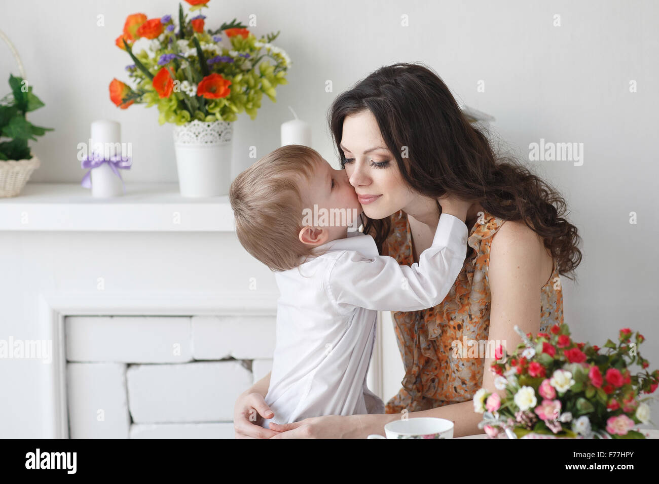 Beautiful blond boy kissing a girl mom in the room with a spring ...