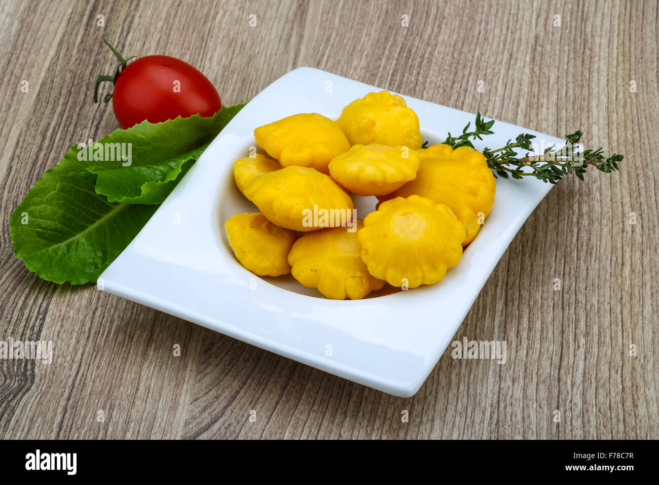 Yellow Pickled patissons with thyme leaves on the wood background Stock ...