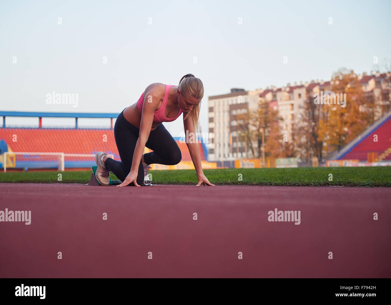 woman sprinter leaving starting blocks on the athletic track. Side view ...