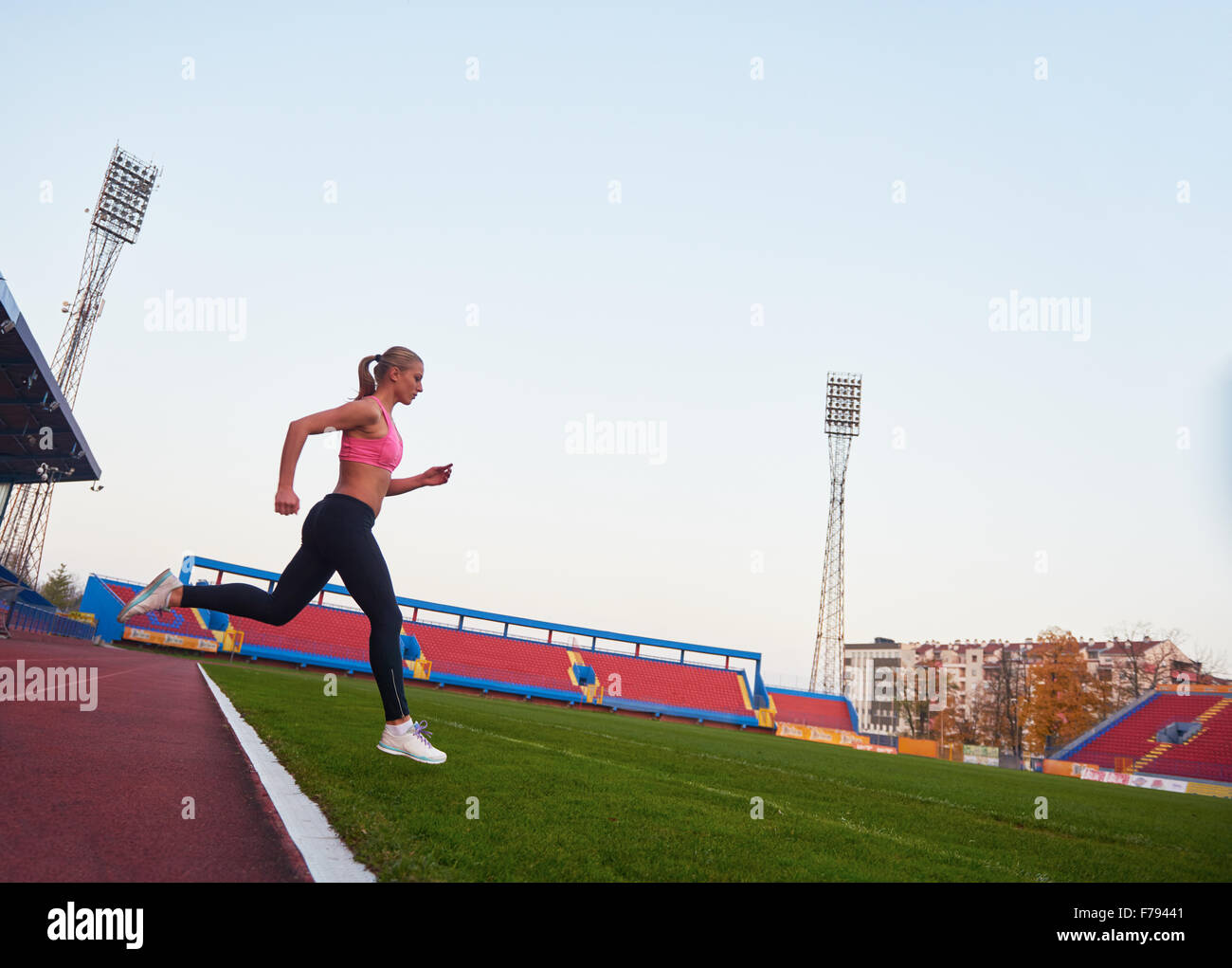Athletic woman running onrace track Stock Photo - Alamy