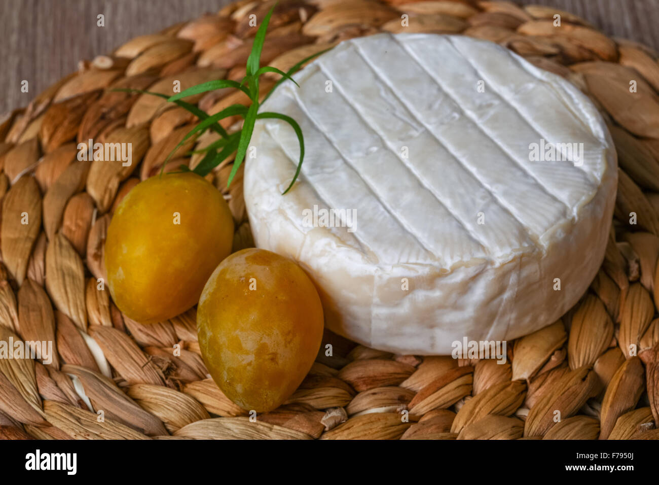 Brie cheese with yellow plums and estragon leaves Stock Photo - Alamy