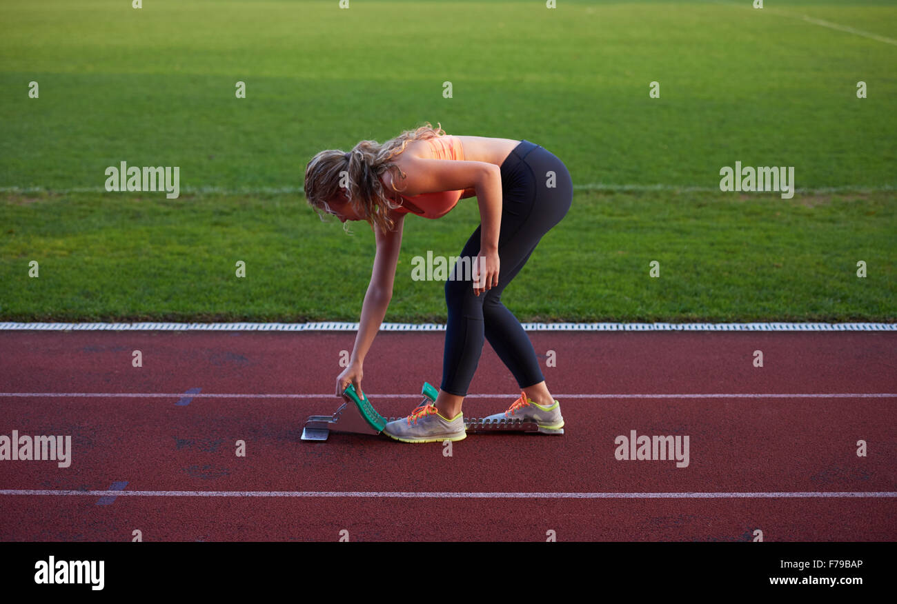 woman sprinter leaving starting blocks on the athletic track. Side view ...