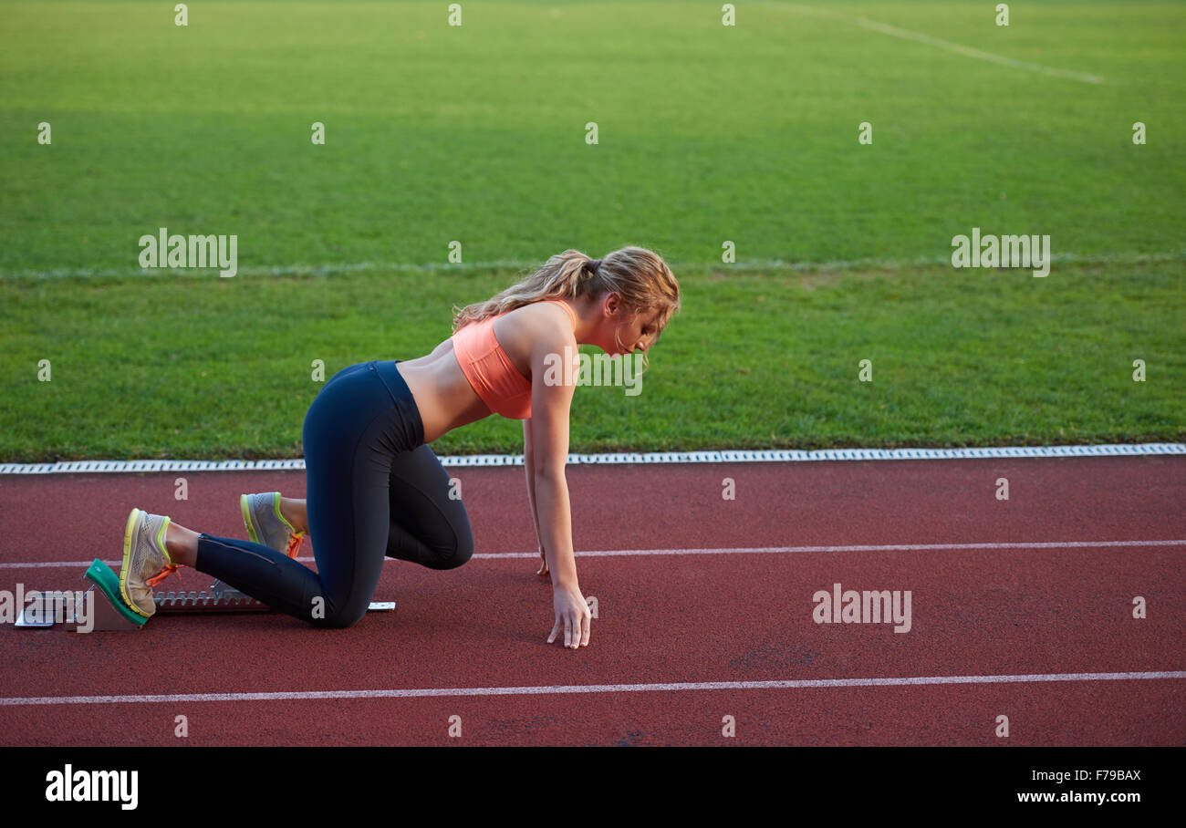 woman sprinter leaving starting blocks on the athletic track. Side view ...