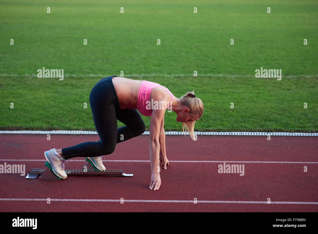 woman sprinter leaving starting blocks on the athletic track. Side view ...