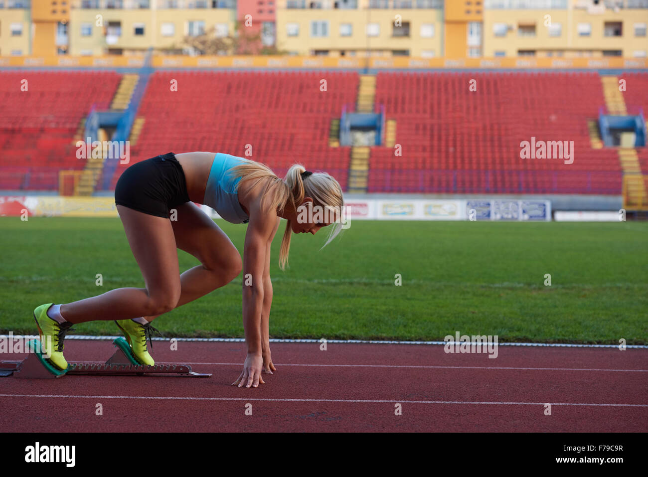 woman sprinter leaving starting blocks on the athletic track. Side view ...