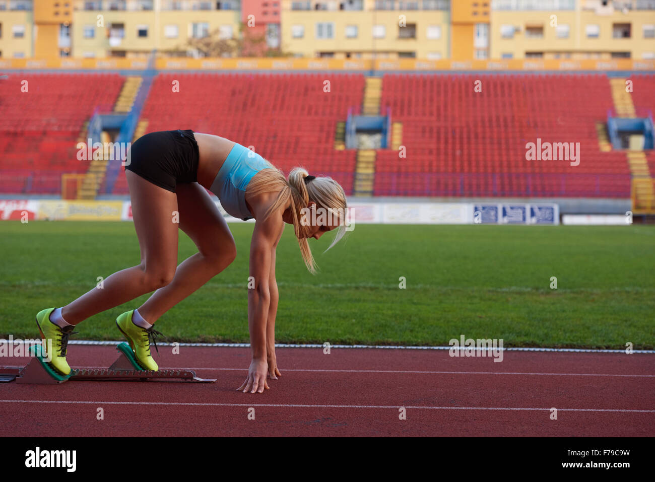 woman sprinter leaving starting blocks on the athletic track. Side view ...