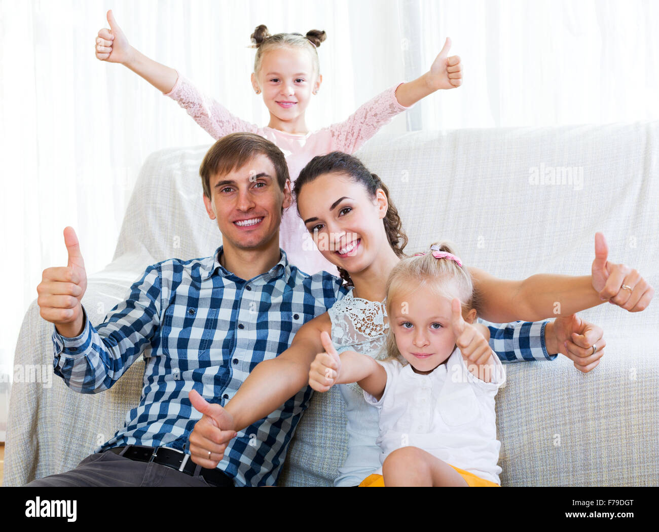 Happy parents with two daughters relaxing at home Stock Photo - Alamy