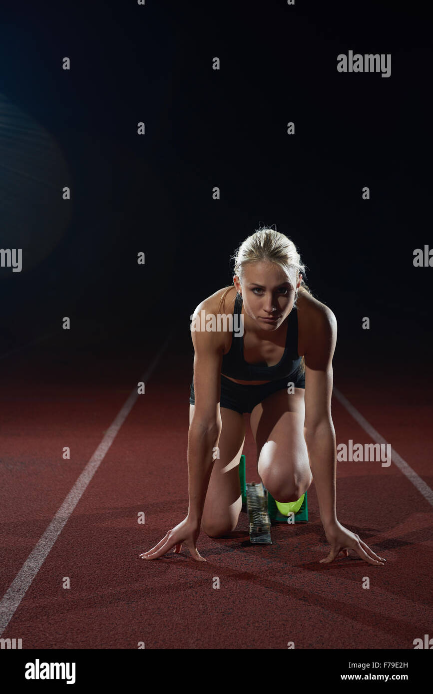 woman sprinter leaving starting blocks on the athletic track. Side view ...