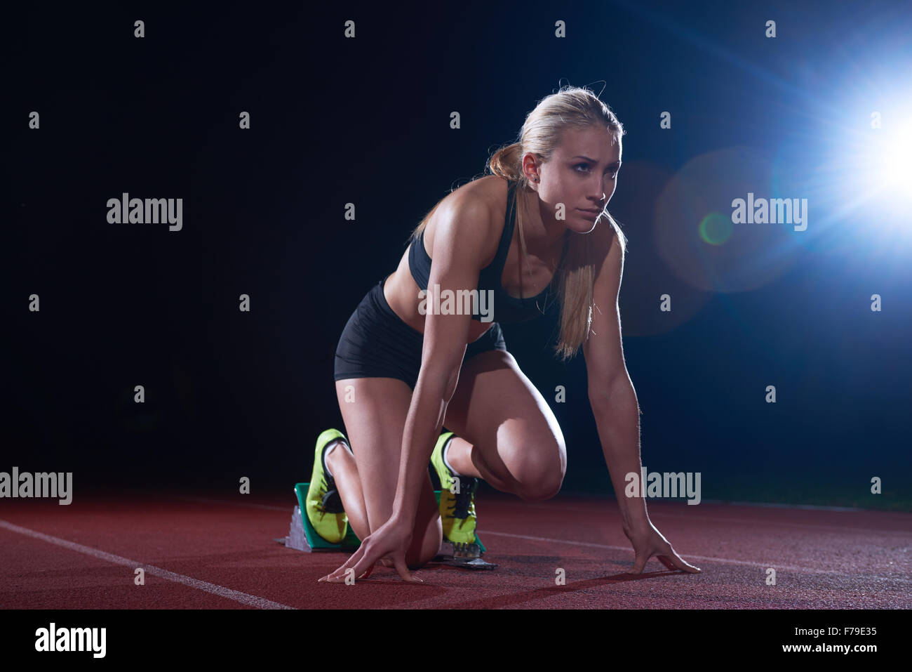 woman sprinter leaving starting blocks on the athletic track. Side view ...