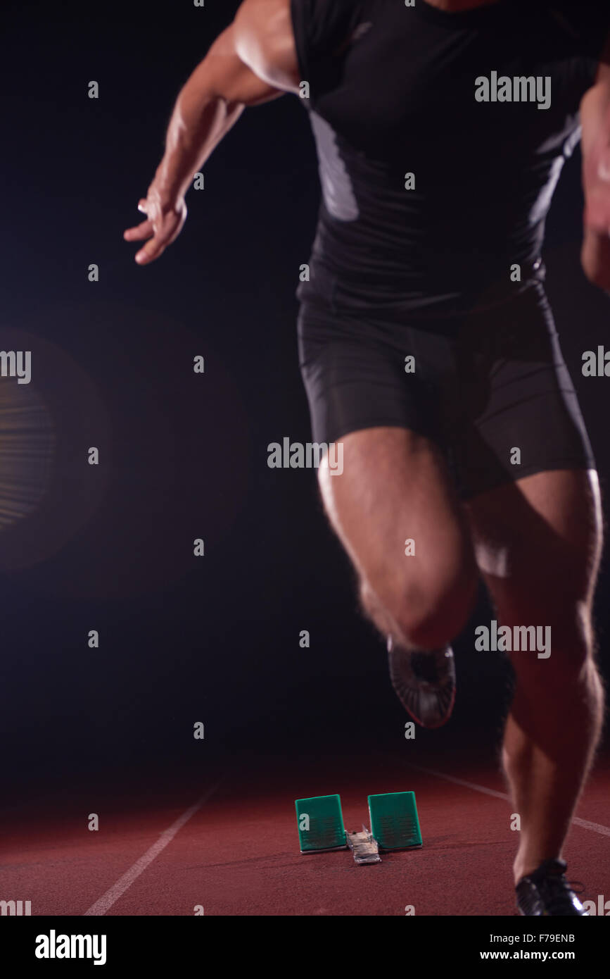 woman sprinter leaving starting blocks on the athletic track. Side view ...