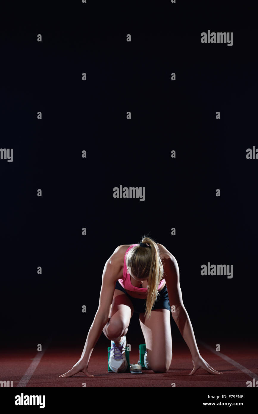 woman sprinter leaving starting blocks on the athletic track. Side view ...