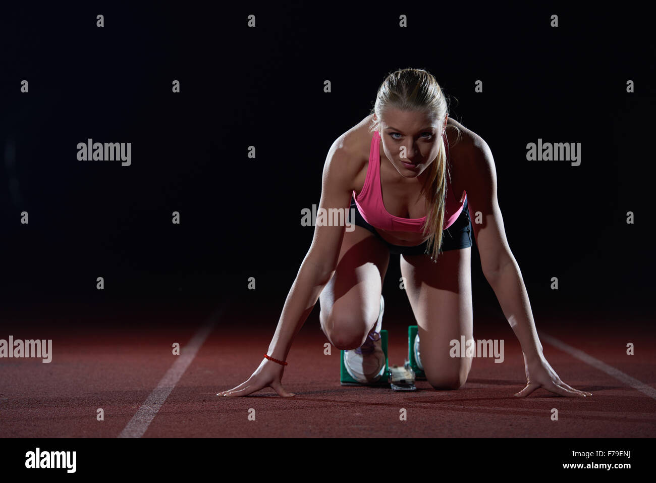 woman sprinter leaving starting blocks on the athletic track. Side view ...