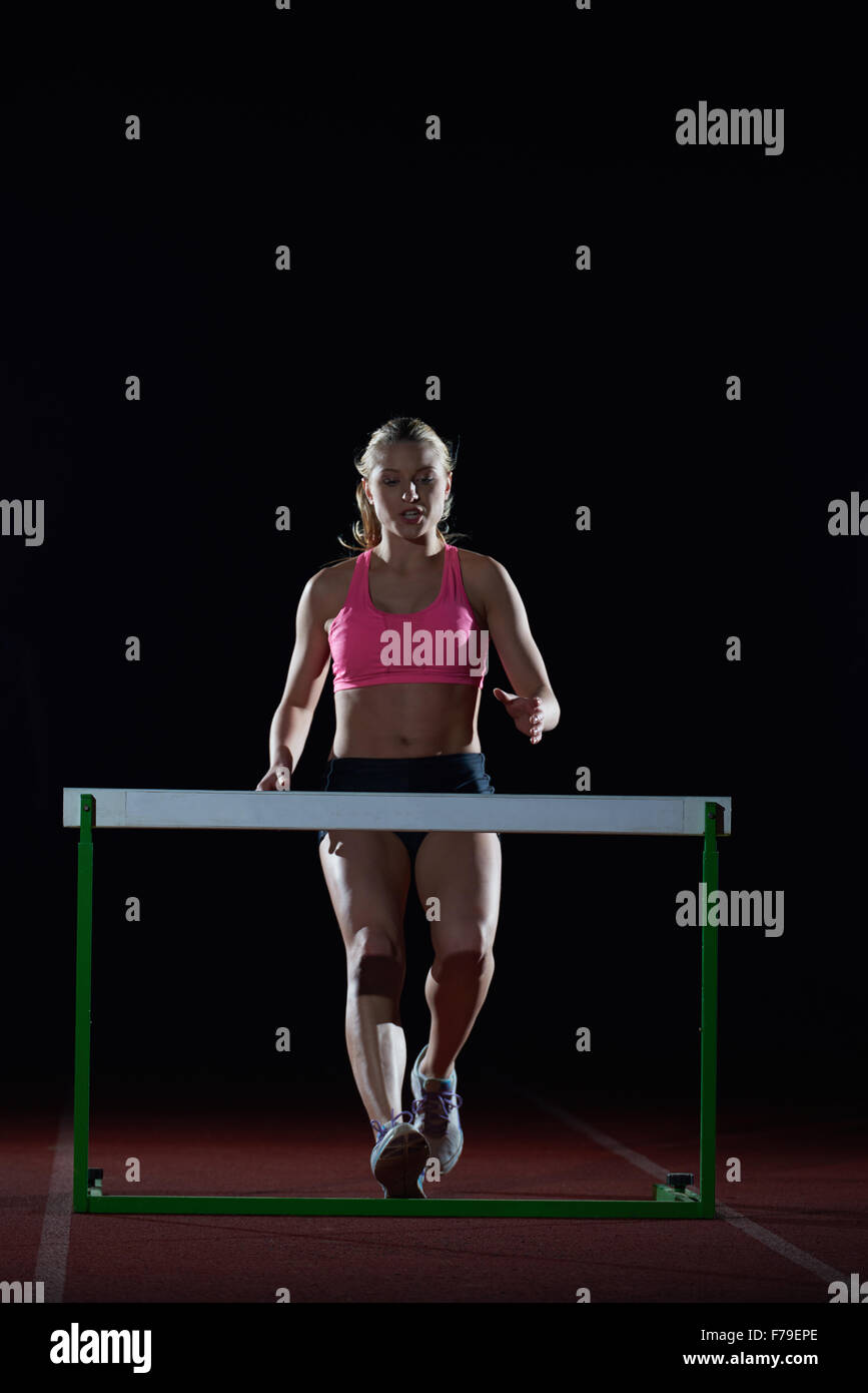 Determined young woman athlete jumping over a hurdles Stock Photo - Alamy
