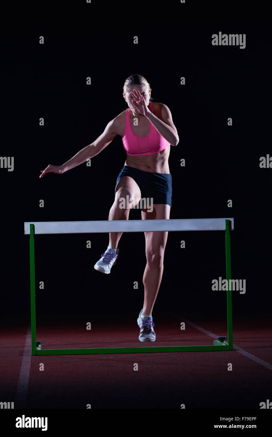 Determined young woman athlete jumping over a hurdles Stock Photo - Alamy
