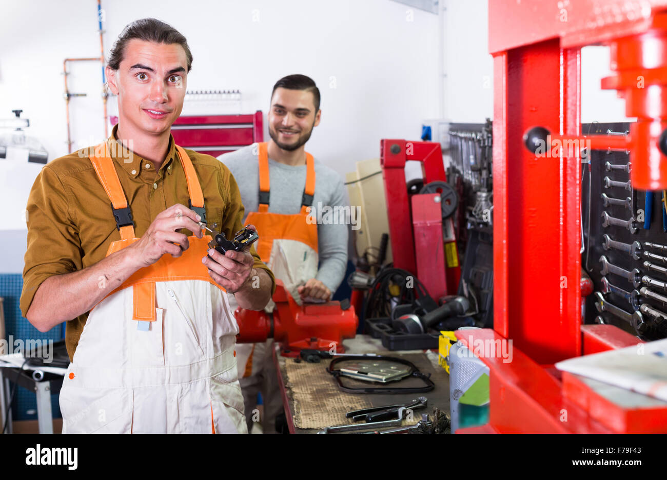 Two happy mechanics toiling in locksmiths workshop and smiling Stock ...