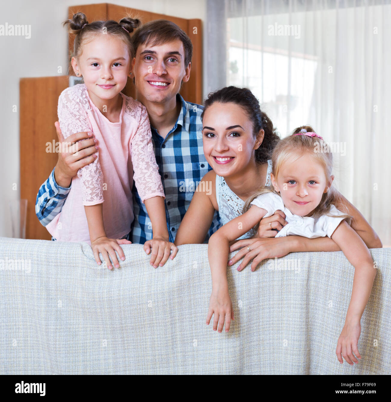 Relaxed family of four happy persons posing in domestic interior Stock ...