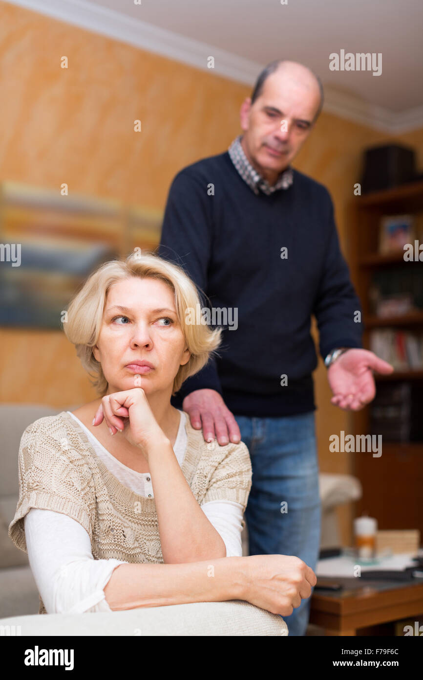 Angry senior mature woman and man after quarrel at home. Focus on woman ...