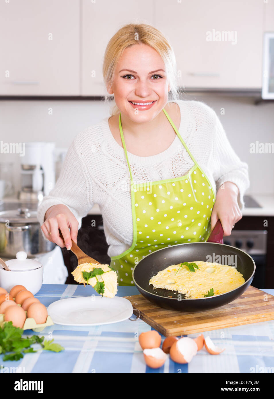Smiling young housewife making omlet in kitchen Stock Photo - Alamy
