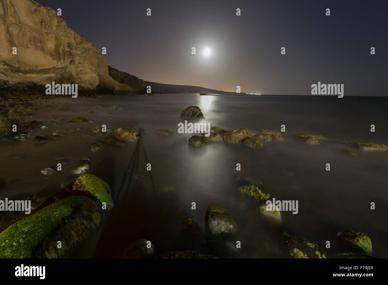 Night image of a beach with rocks and moon Stock Photo - Alamy