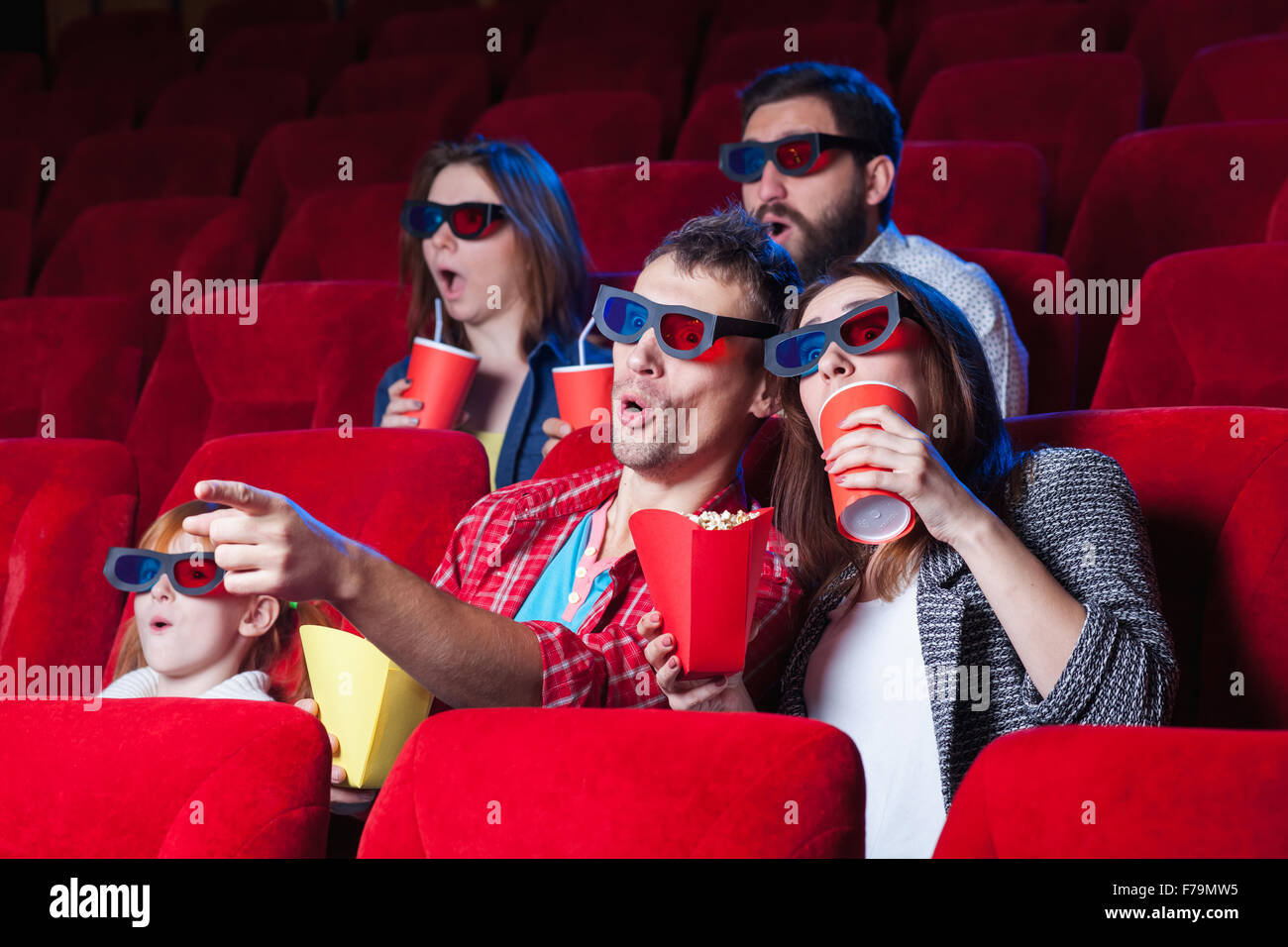The spectators sitting in the cinema and watching movie with cups of ...