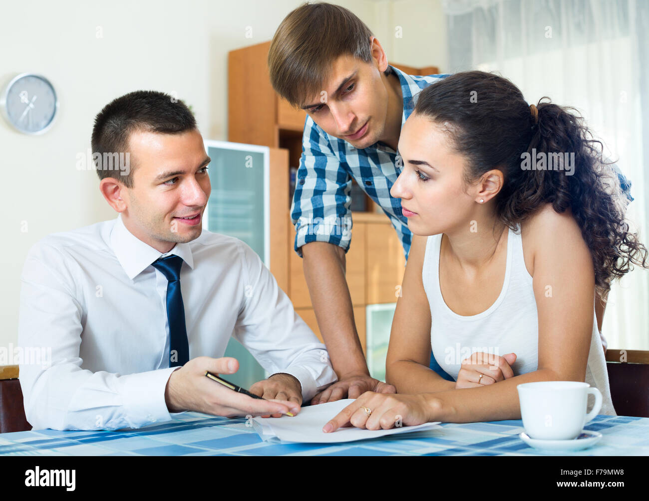 Smiling insurance agent consulting young couple in home interior Stock ...