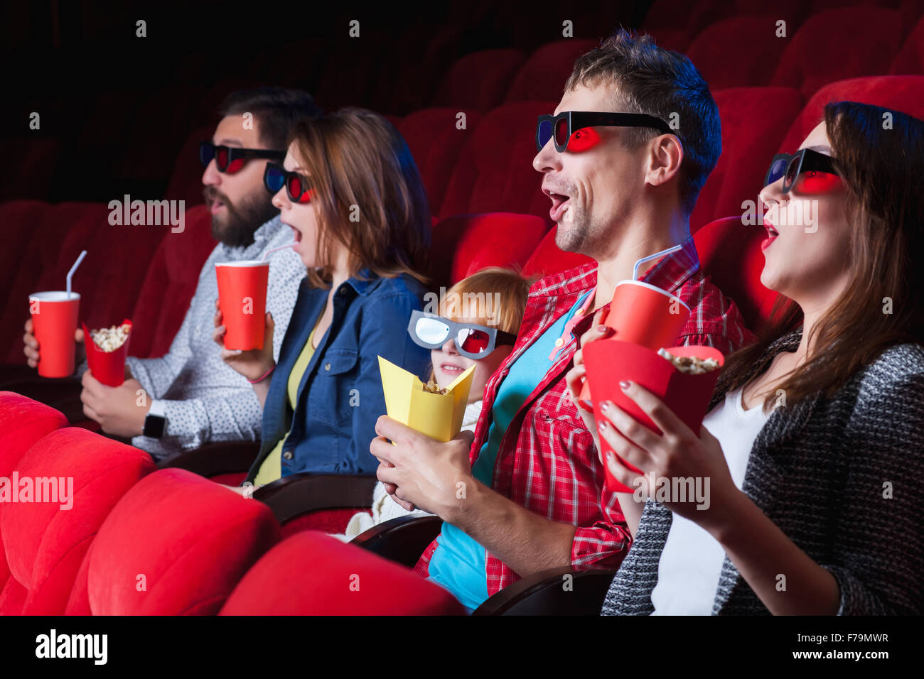 The spectators sitting in the cinema and watching movie with cups of ...