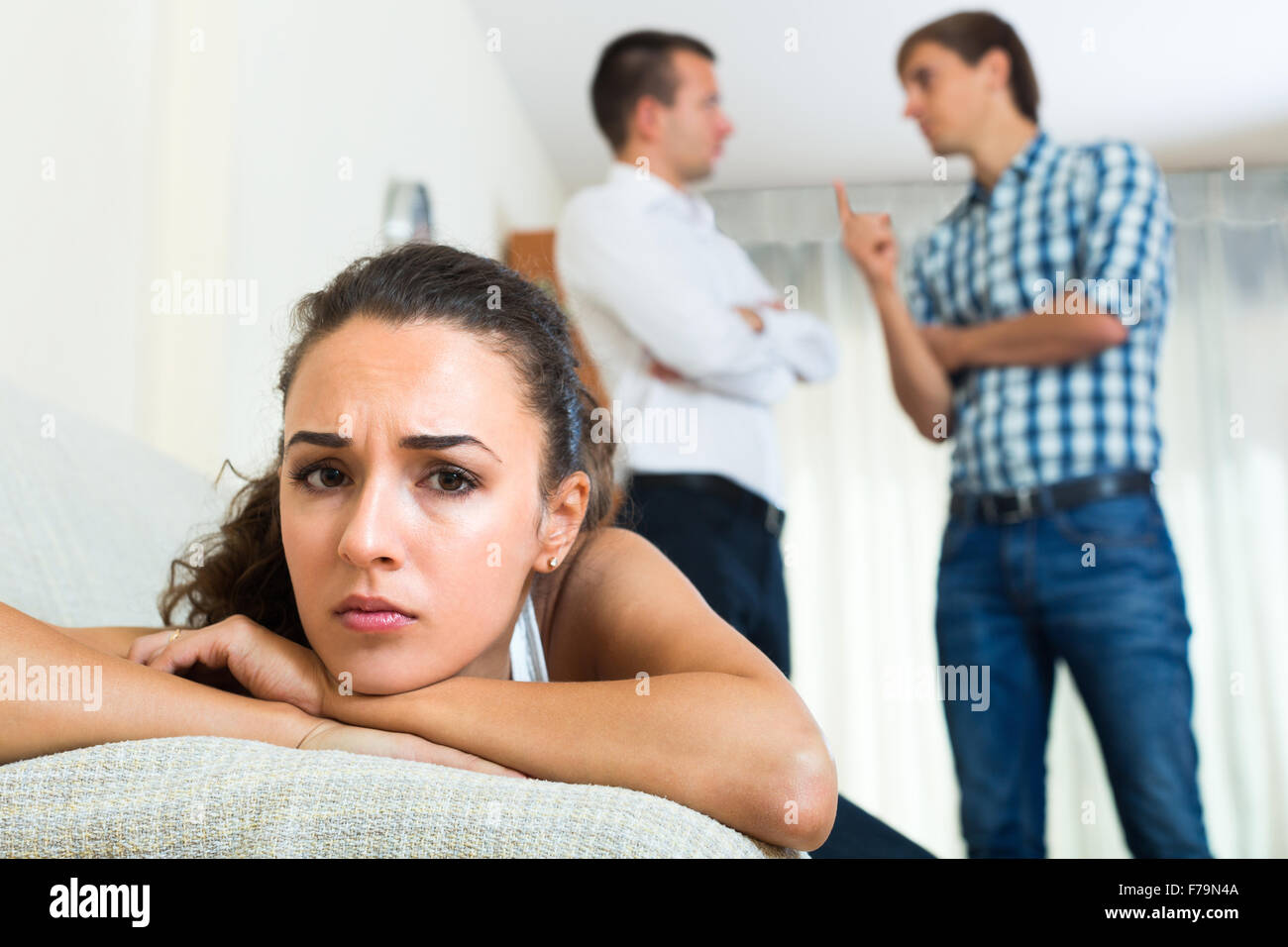 Two young guys and sad brunette girl apart after conflict indoors Stock ...