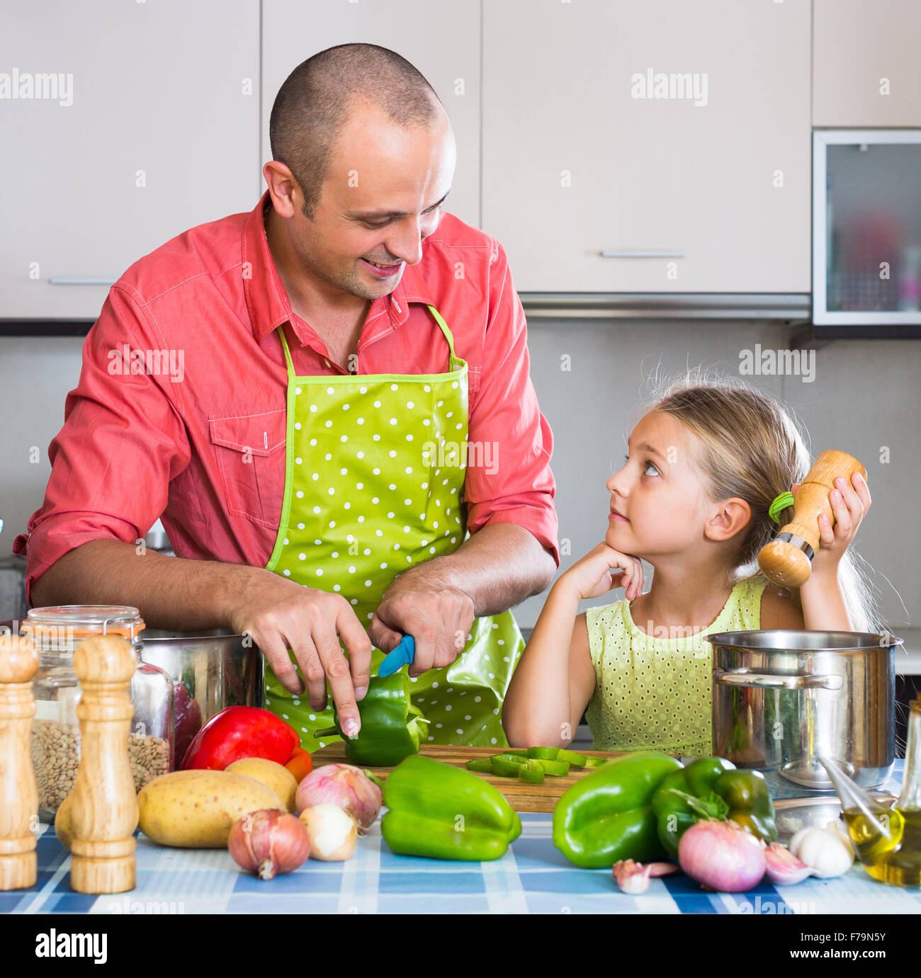 Happy smiling man and cute little girl cooking vegetables in the ...