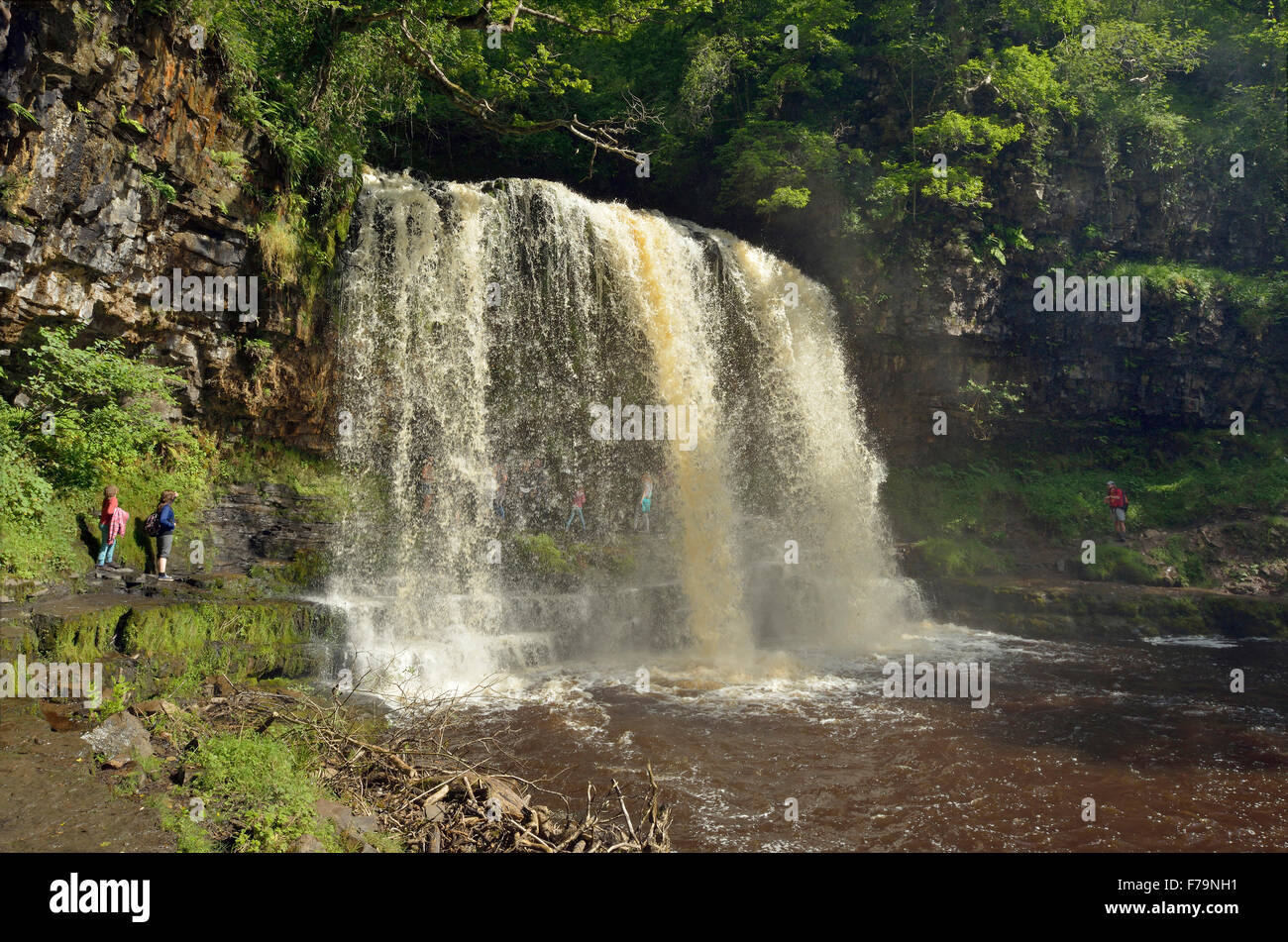 People walking behind Sgwd yr Eira Waterfall; Afon Hepste River Brecon ...