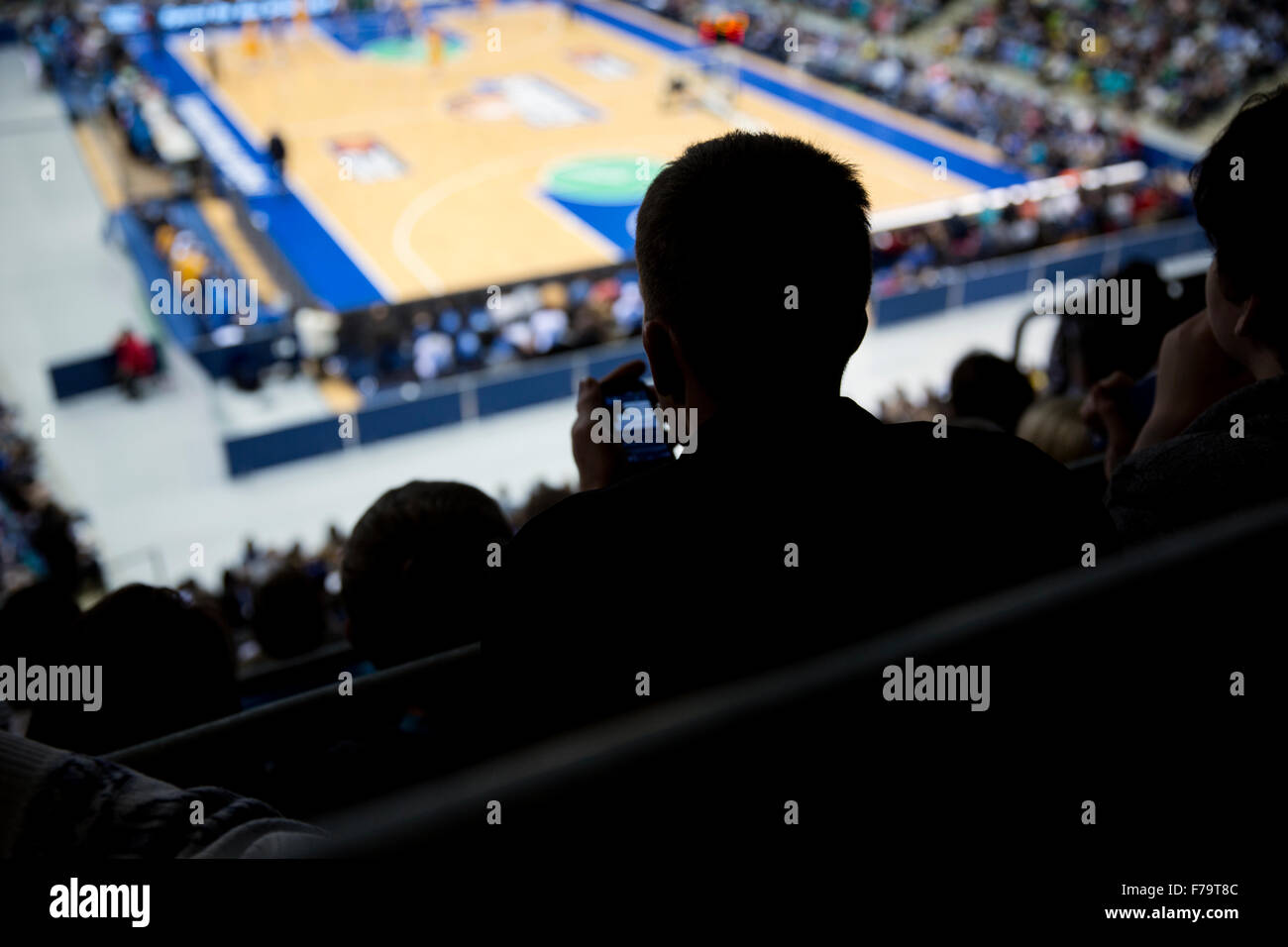 A spectator at a professional basketball game taps on the screen of his ...