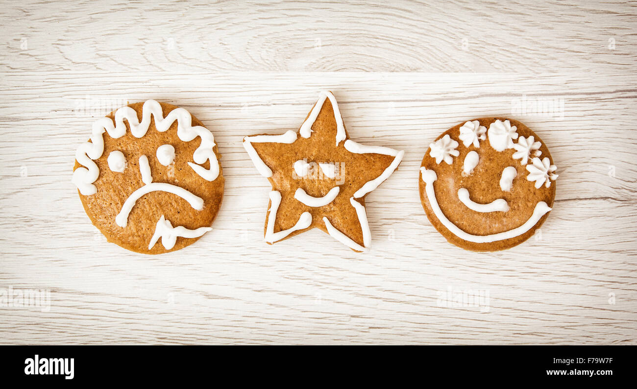 Three tasty gingerbread smiley faces on the wooden background ...