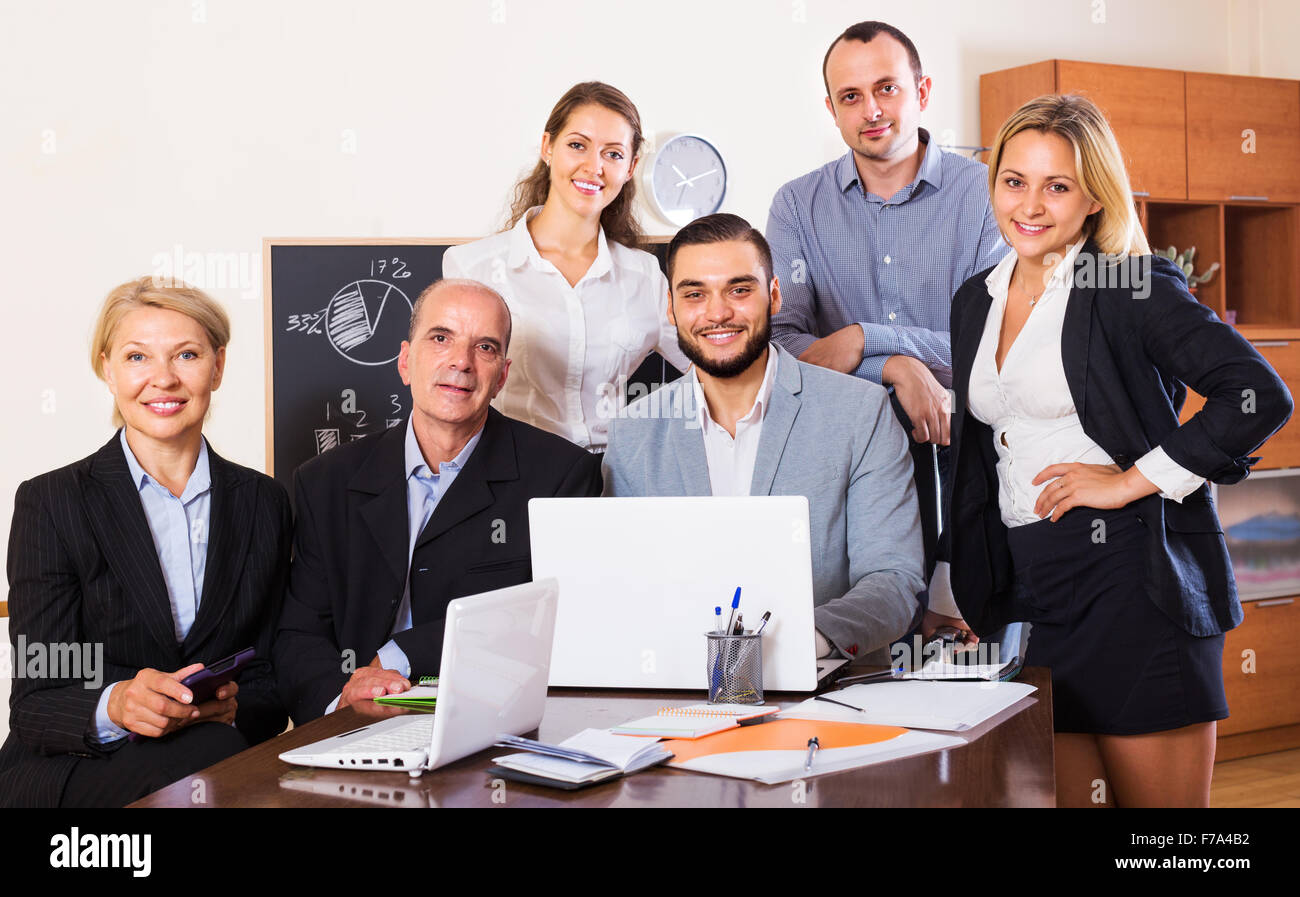 Portrait of friendly european employees sitting at desk Stock Photo - Alamy
