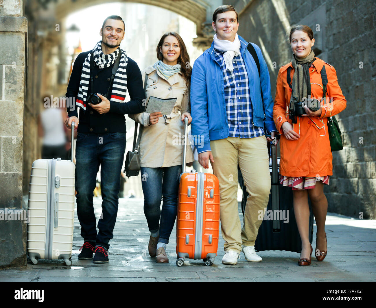Group of beautiful friends walking through street with camera and ...