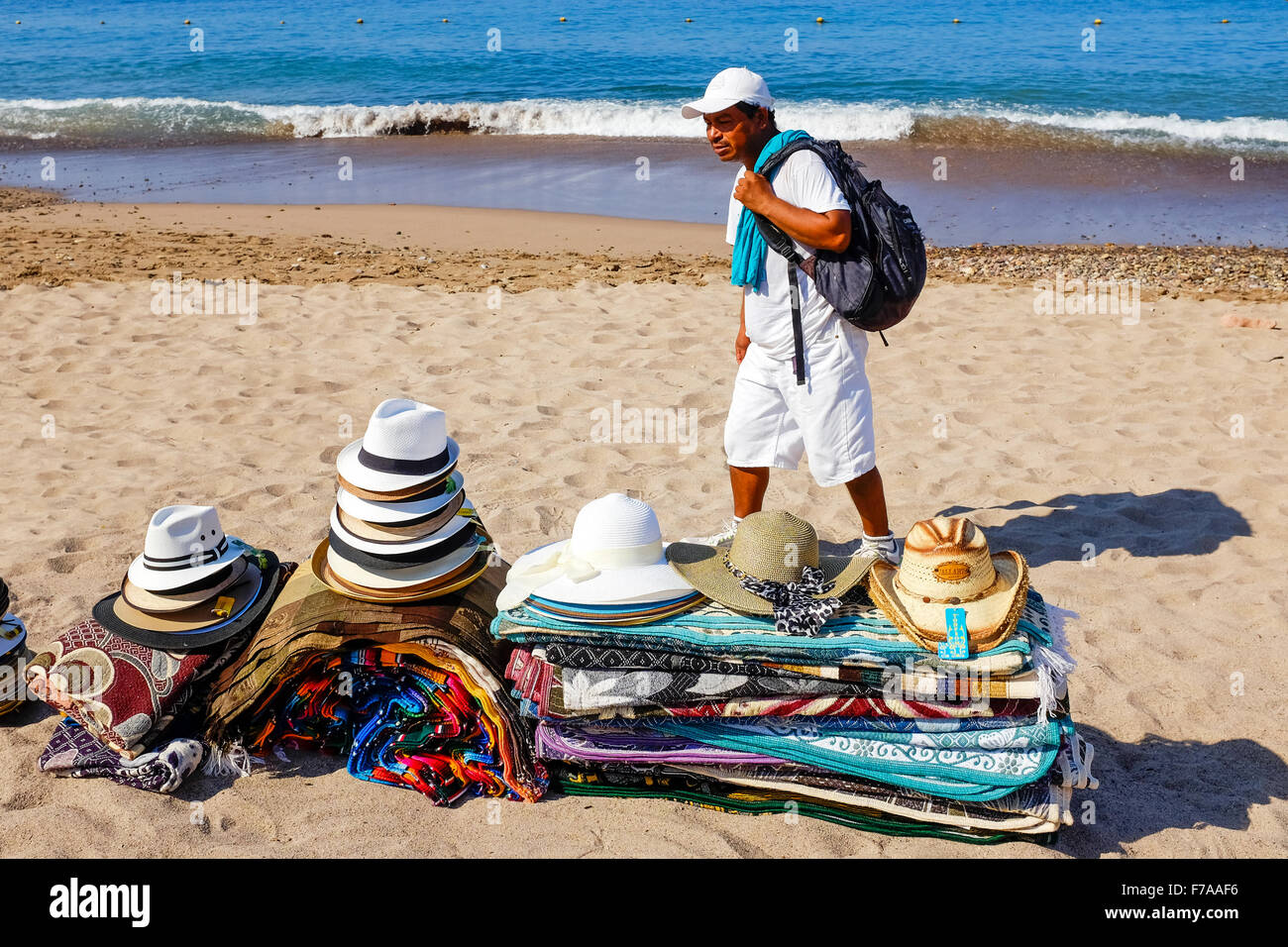Man selling hats, mats, rugs and clothing on the beach at Puerto ...