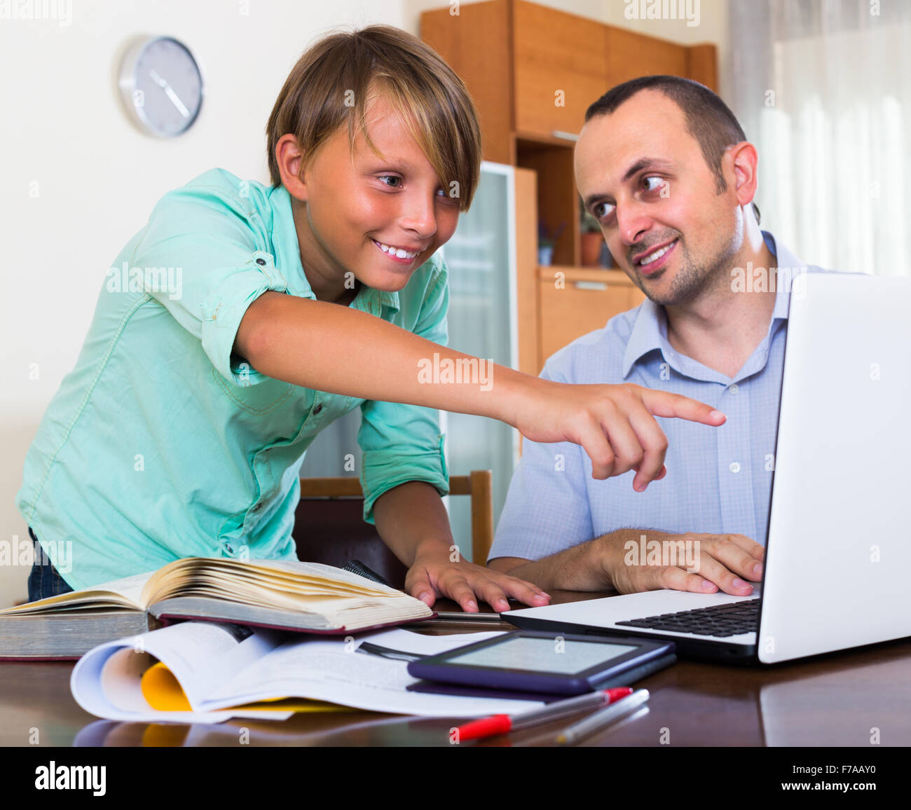 Smiling man helping teenage son to do homework at home Stock Photo - Alamy
