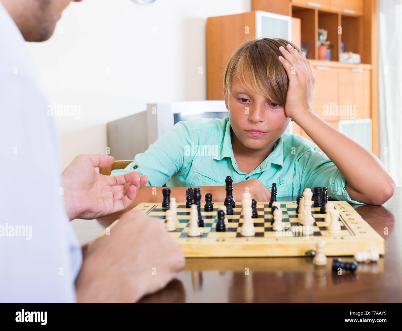 Father and boy playing chess, boy losing Stock Photo - Alamy