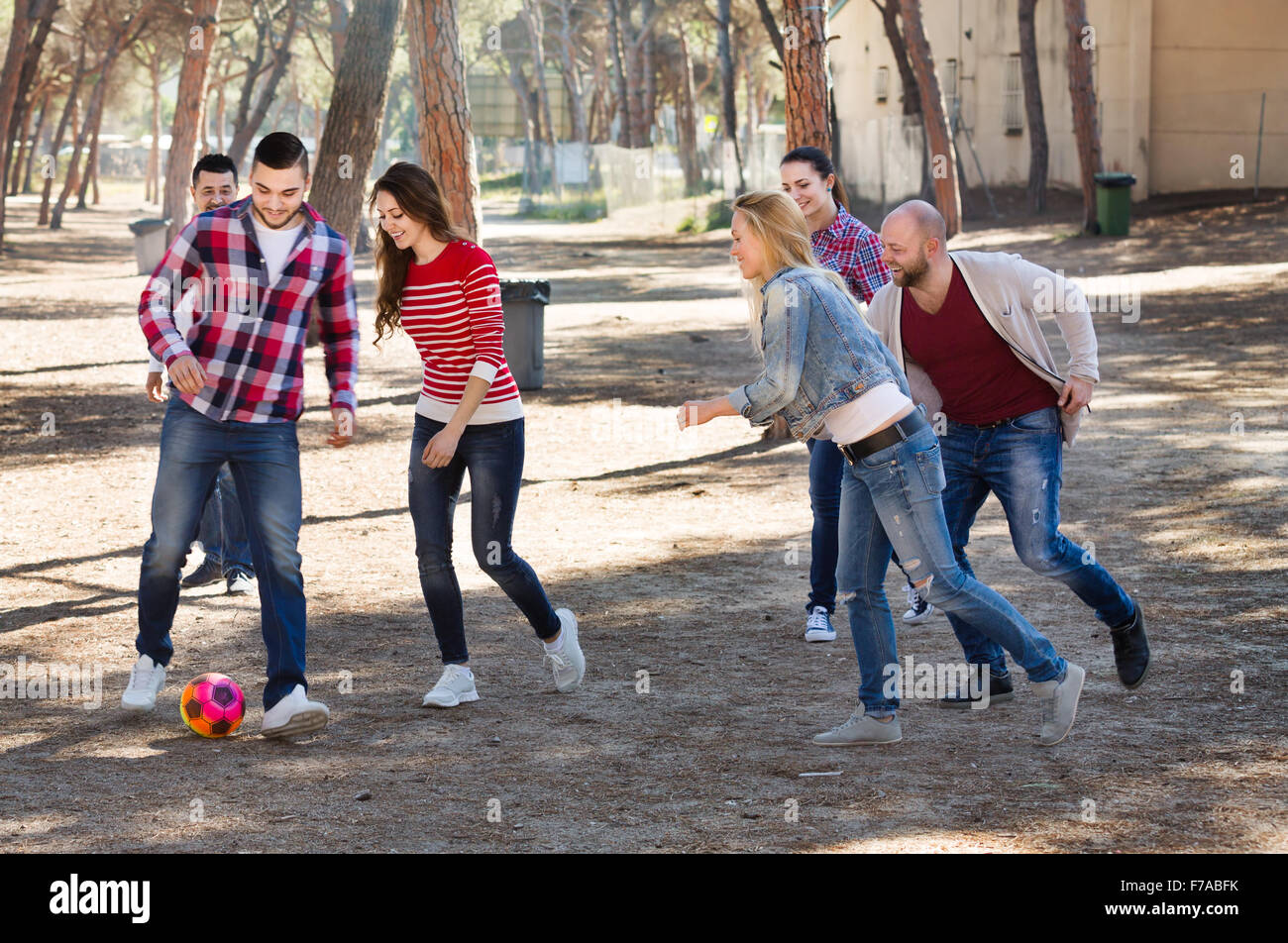 Several friends running with ball and laughing Stock Photo - Alamy