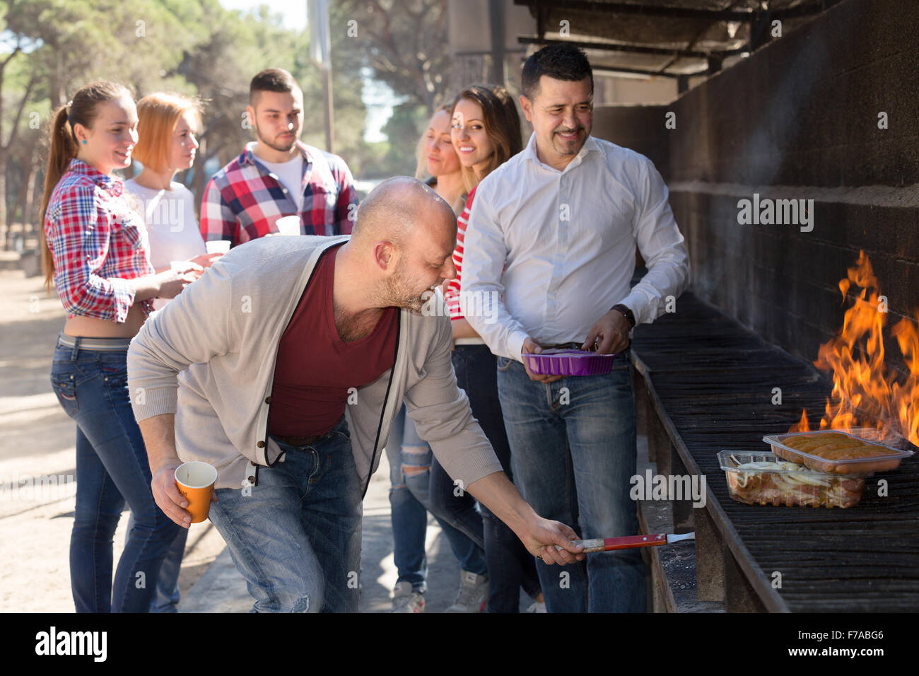 Happy colleagues making grill at summer corporate party outdoor ...