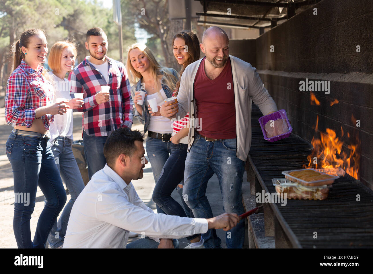 Happy colleagues making grill at corporate party outdoor. Selective ...