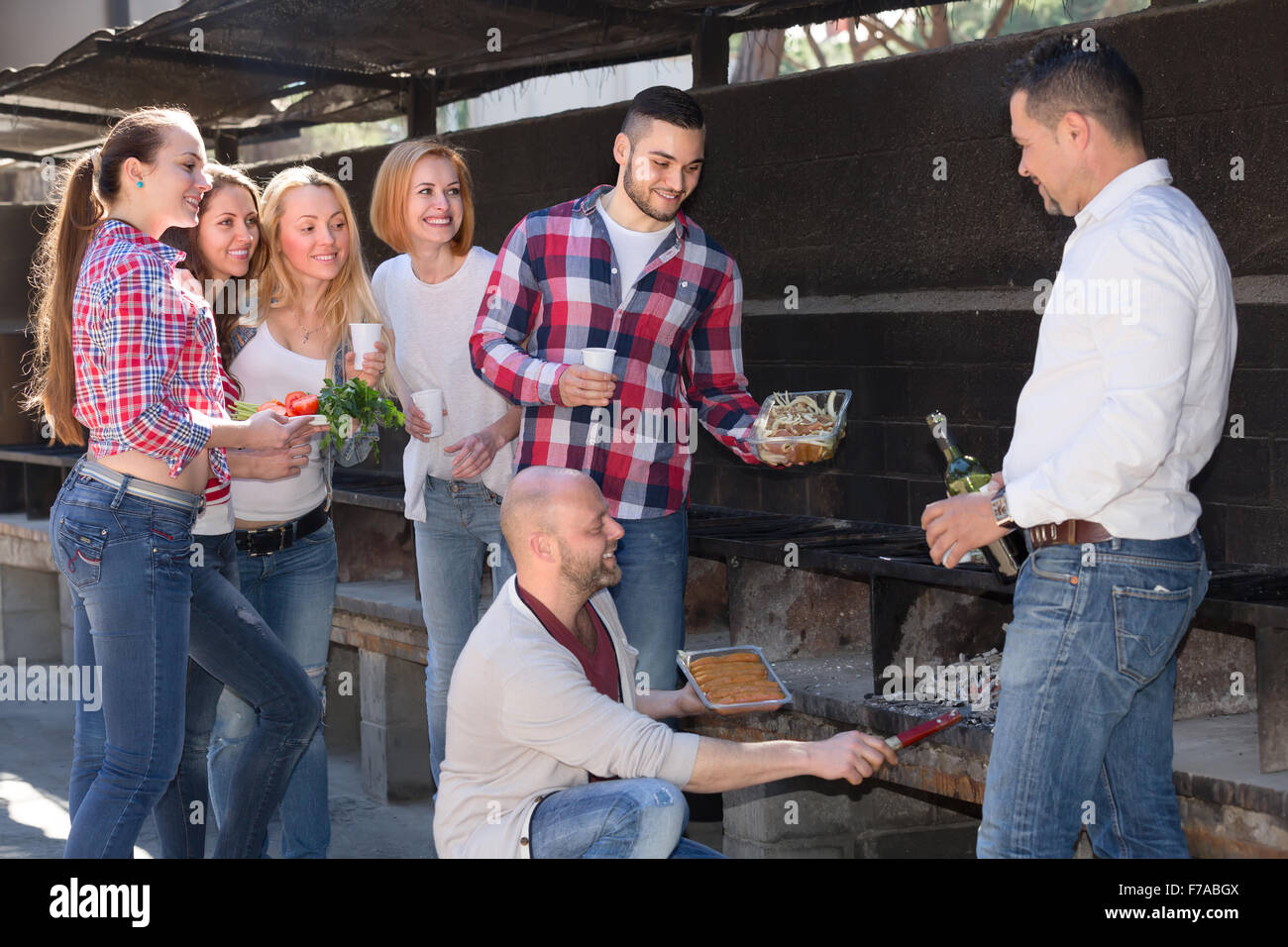 Group of smiling friends making grill at summer corporate party ...