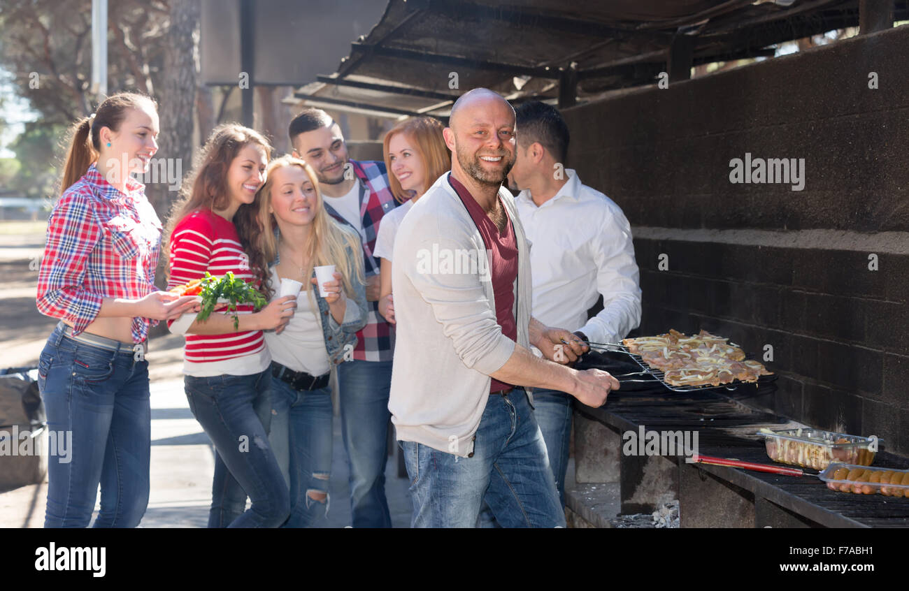 Group of happy friends making grill at summer outdoors. Selective focus ...