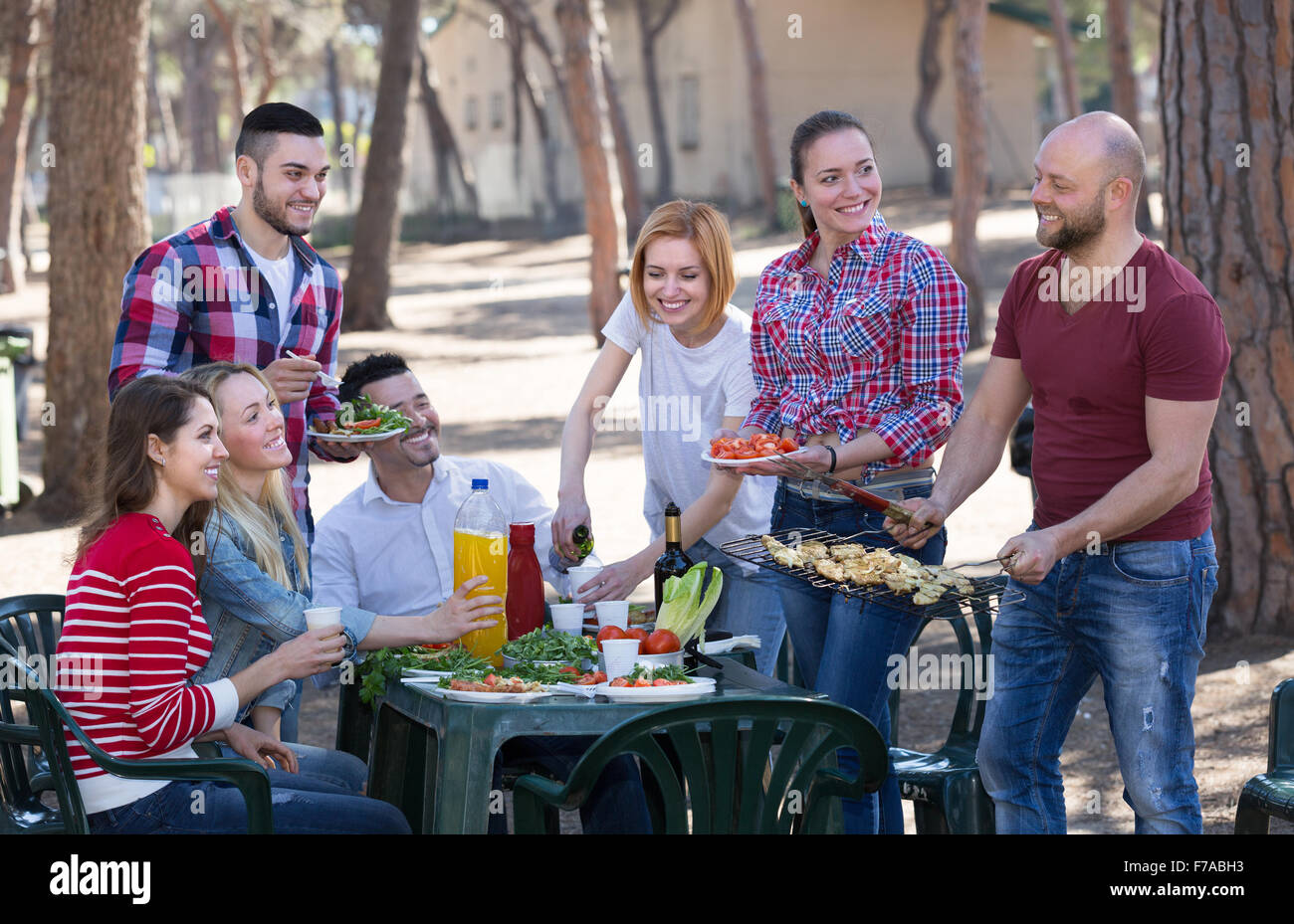 Cheerful smiling colleagues making grill at corporate party outdoor ...