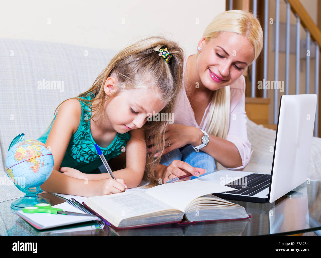 Portrait of positive adult woman and her child having a lesson indoors ...